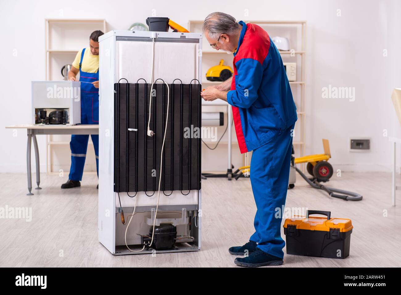 The two contractors repairing fridge at workshop Stock Photo - Alamy