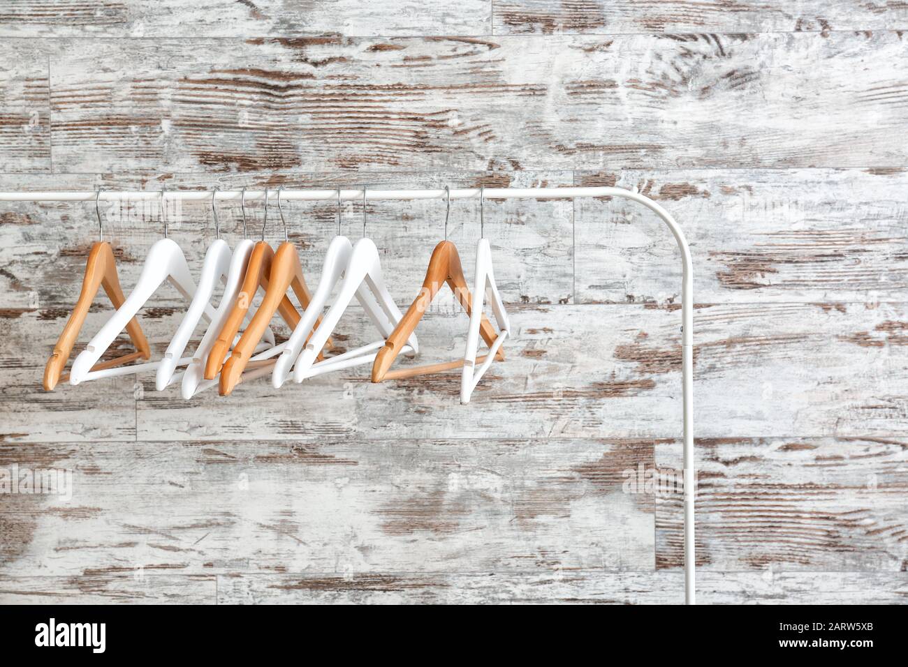 Rack with clothes hangers against wooden wall Stock Photo - Alamy