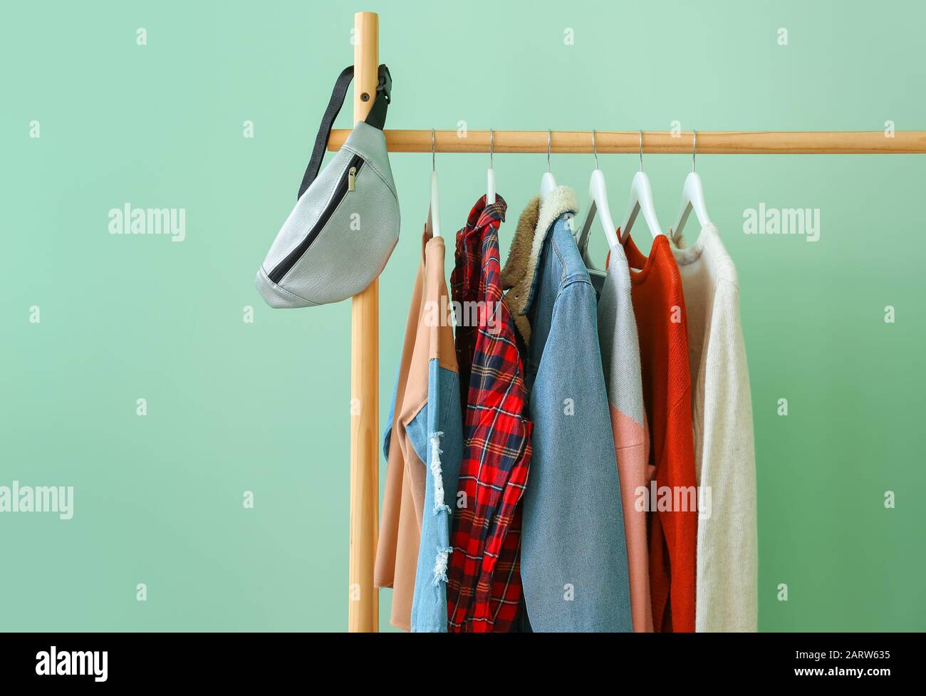 Rack with hanging clothes on color background Stock Photo - Alamy