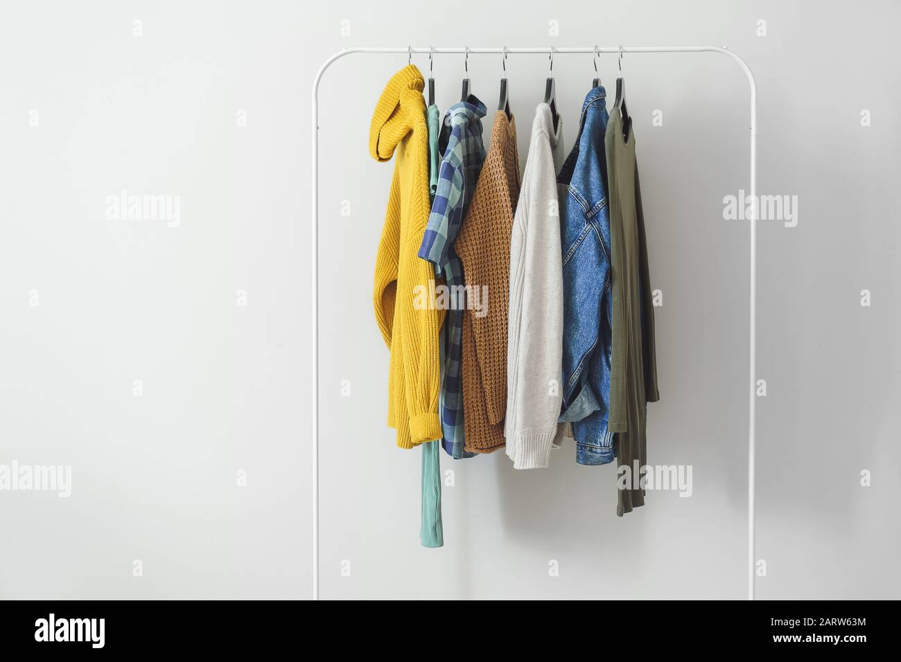 Rack with hanging clothes on light background Stock Photo - Alamy