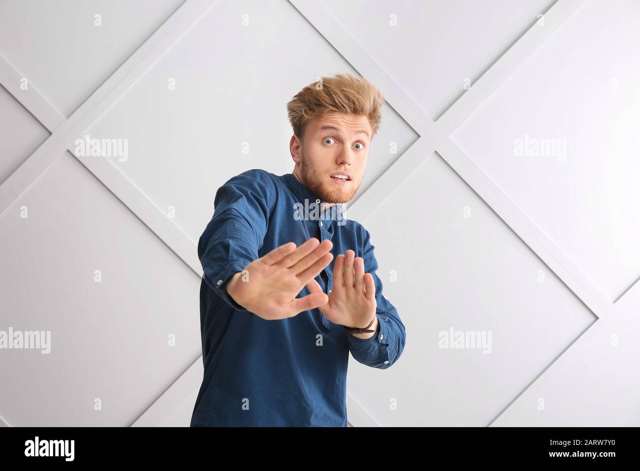 Portrait of afraid man showing stop gesture on grey background Stock ...