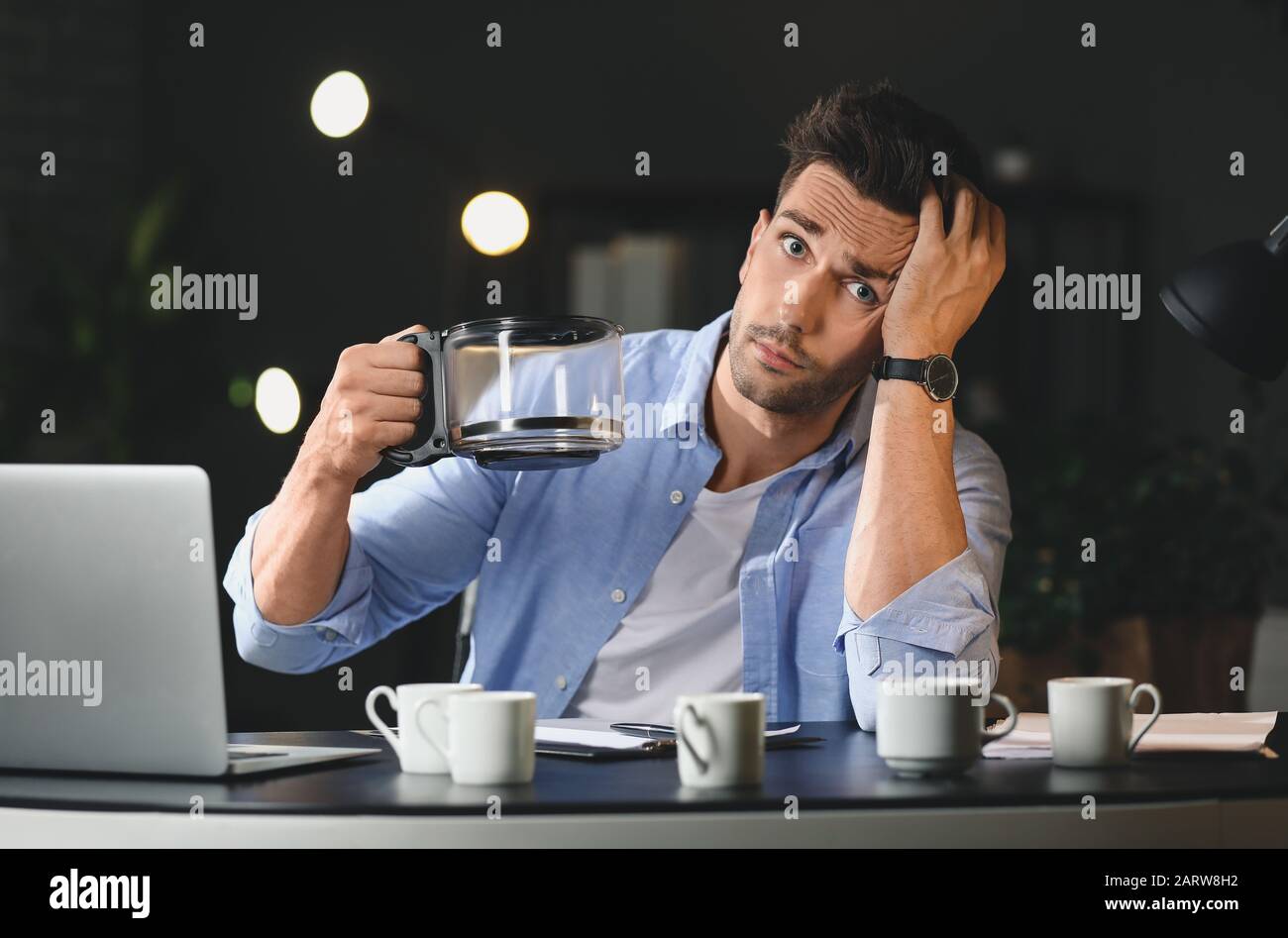 Tired man drinking coffee and trying to meet deadline in office Stock ...
