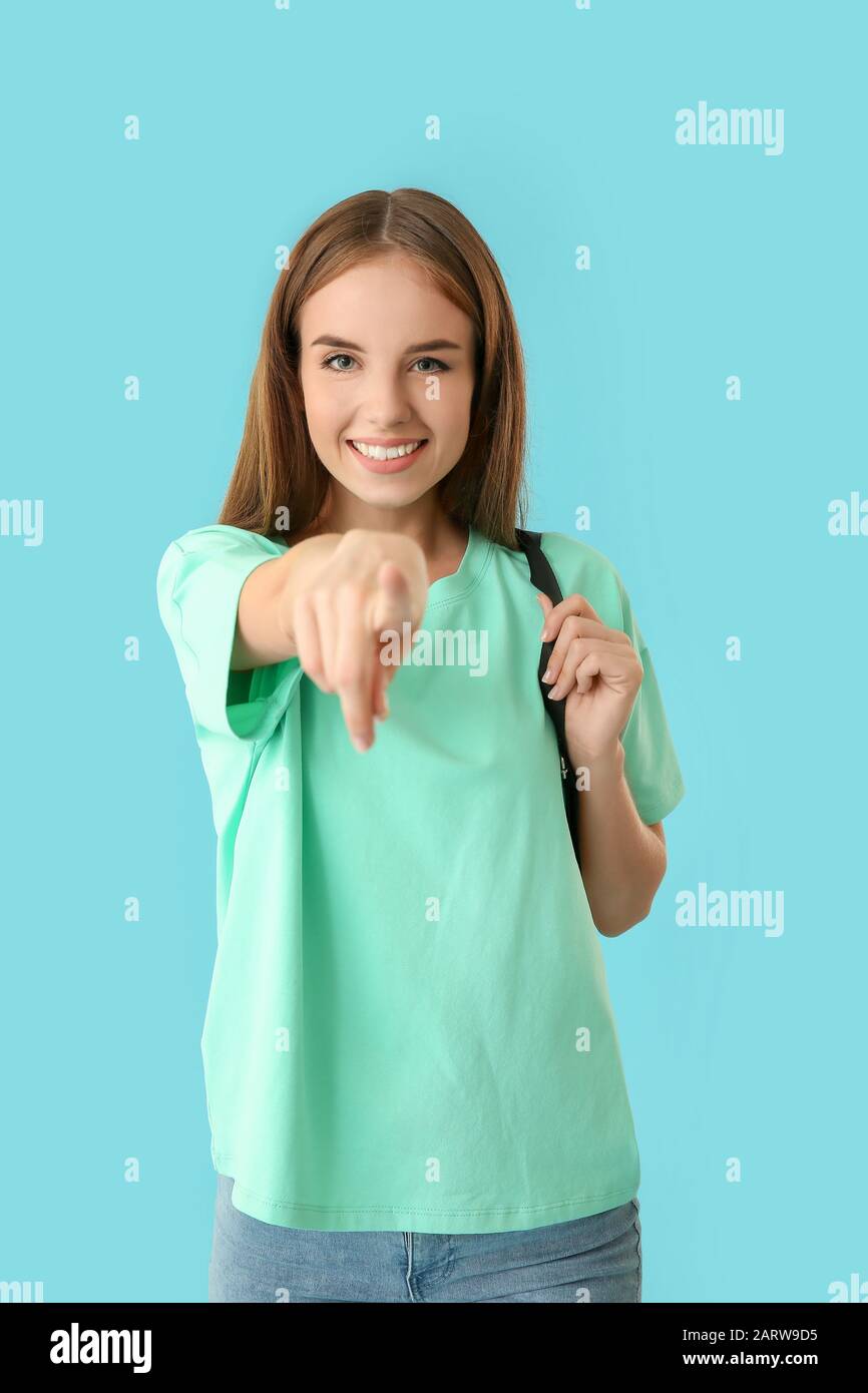 Beautiful female student pointing at viewer on color background Stock ...
