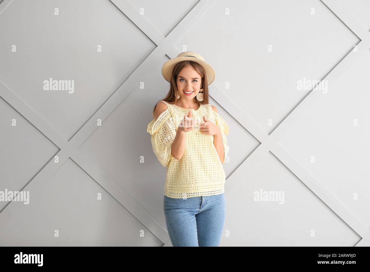Beautiful young woman pointing at viewer on light background Stock ...
