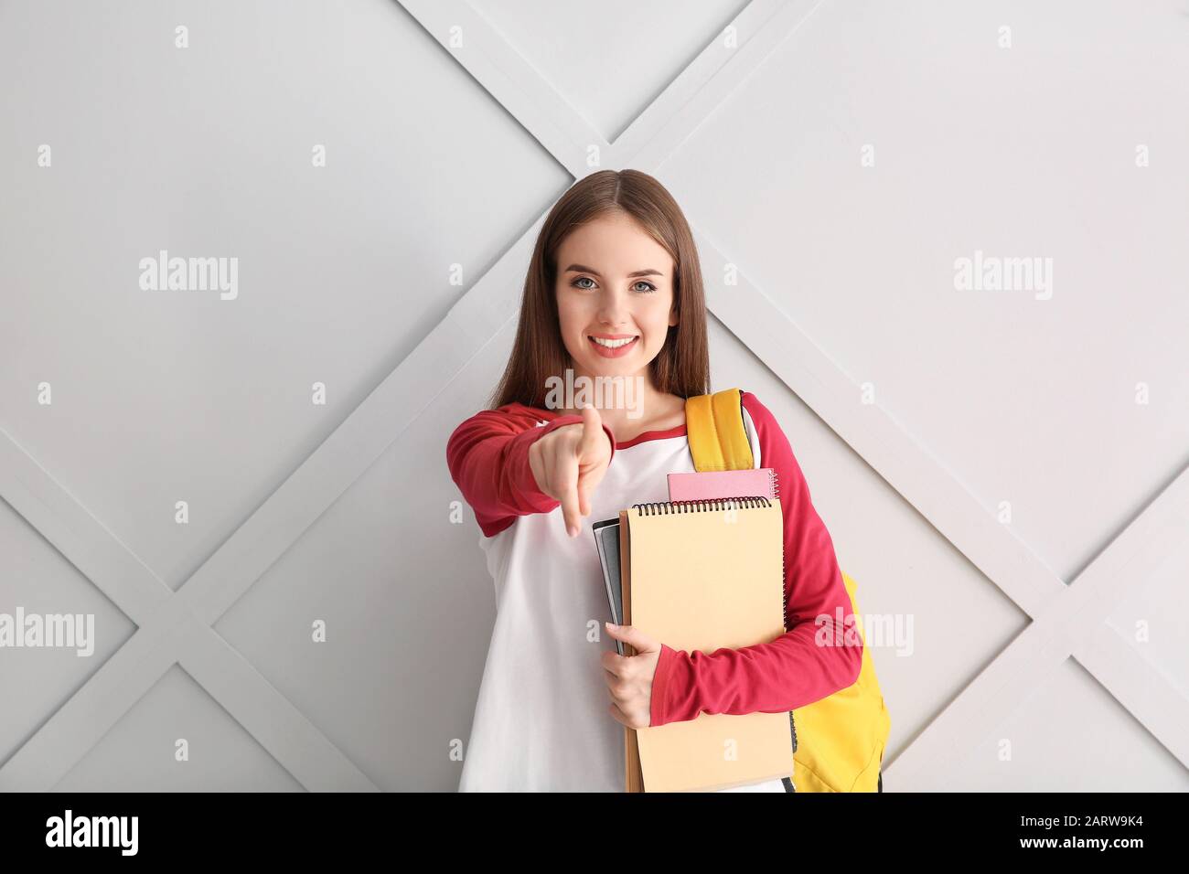 Female student pointing at viewer on light background Stock Photo - Alamy