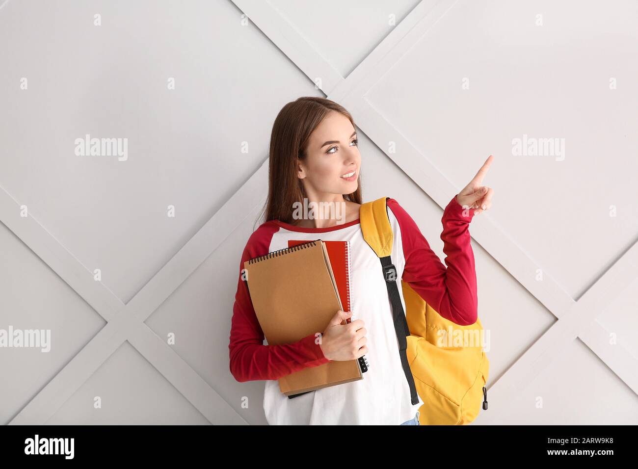 Female student pointing at something on light background Stock Photo ...