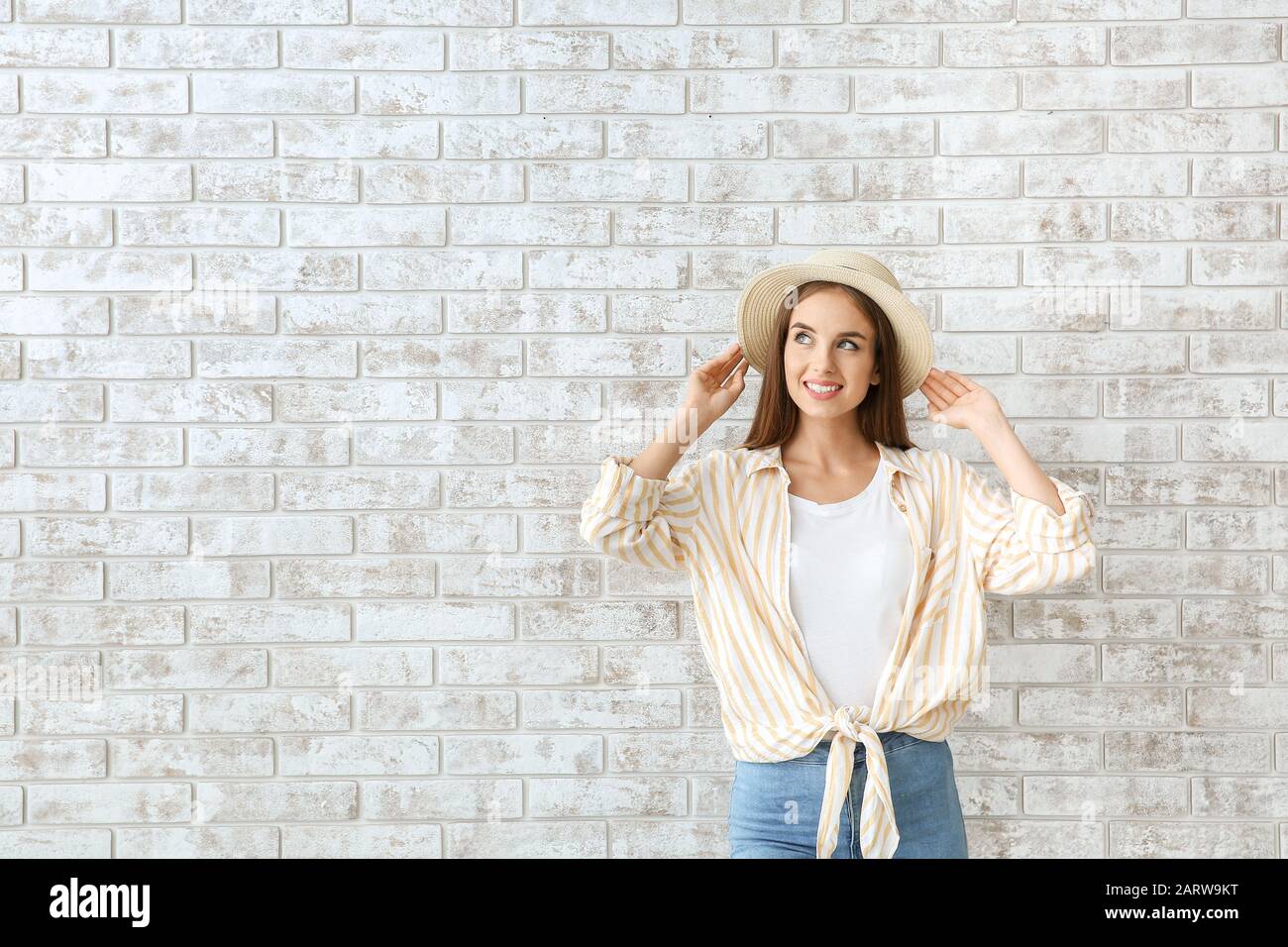 Beautiful young woman against brick wall Stock Photo - Alamy