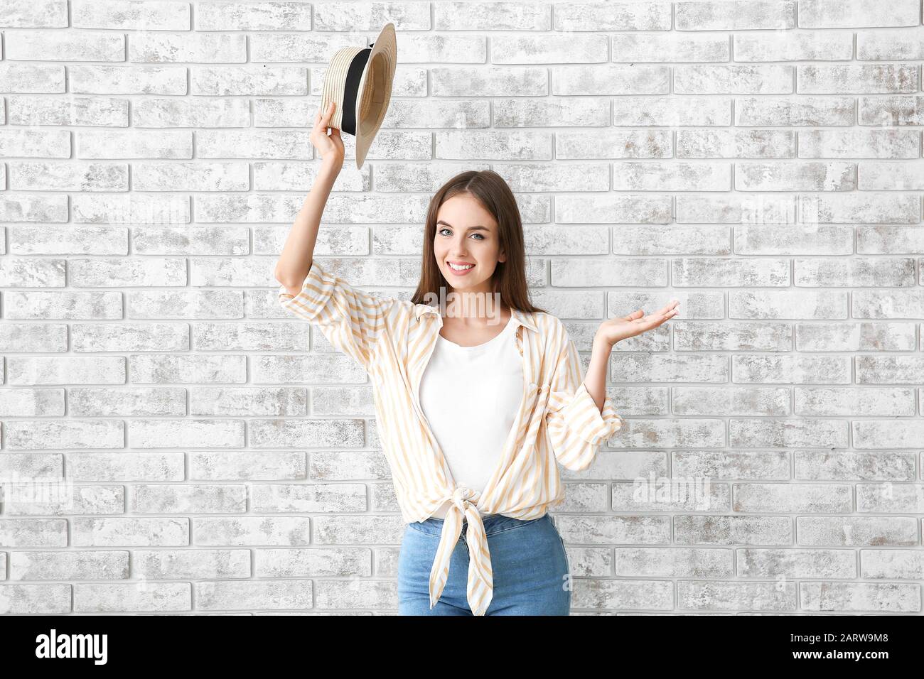 Beautiful young woman against brick wall Stock Photo - Alamy