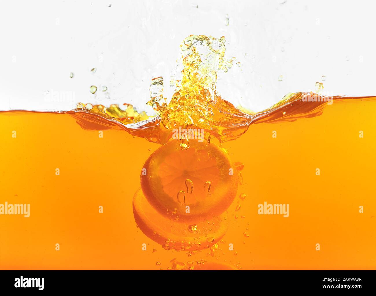 Falling of orange slices into juice on white background Stock Photo - Alamy