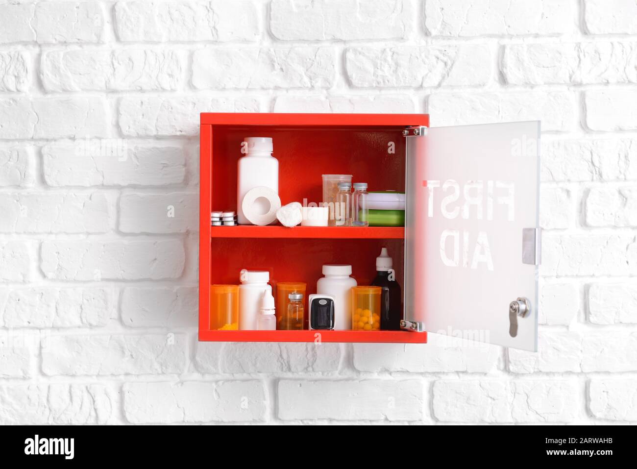 First aid kit hanging on white brick wall Stock Photo - Alamy