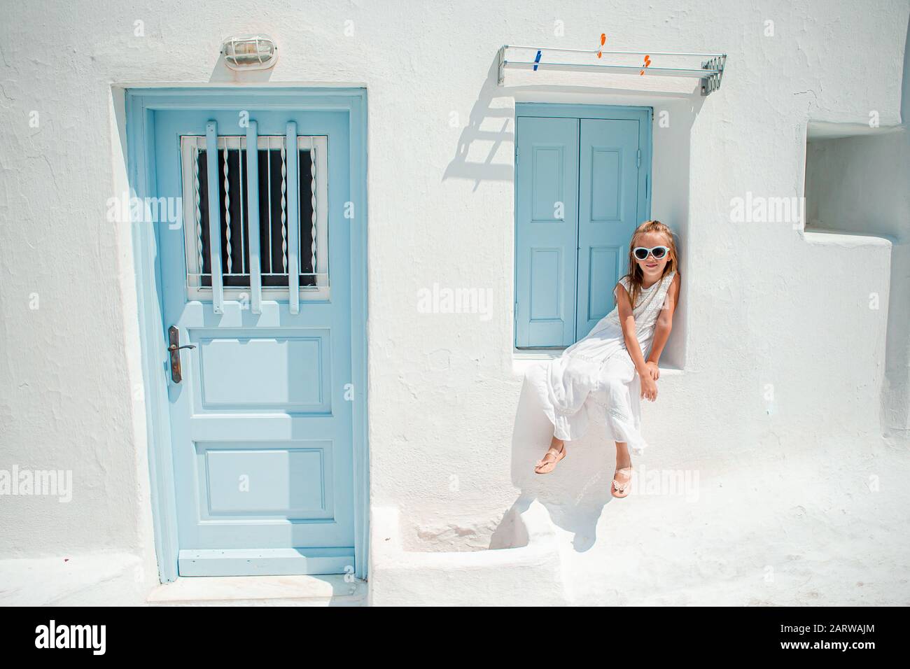 Adorable little girl at old street of typical greek traditional village ...