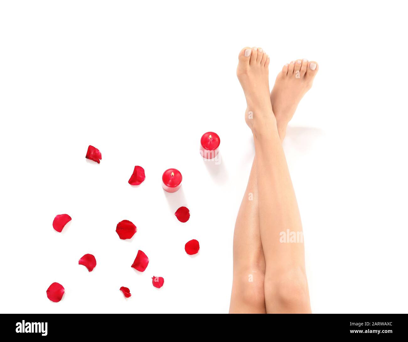 Legs of beautiful young woman, candles and flower petals on white ...