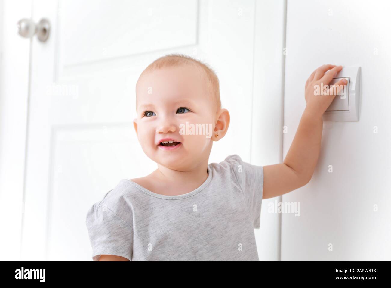 Cute little baby standing near switch in room Stock Photo - Alamy