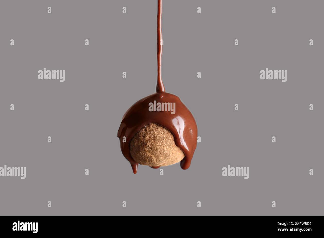 Pouring of chocolate on truffle candy against grey background Stock ...