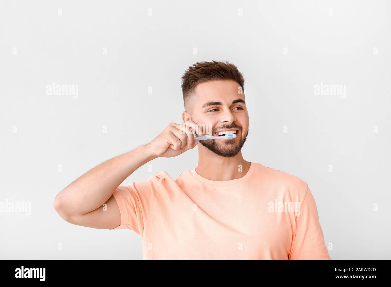 Portrait of man brushing teeth on light background Stock Photo - Alamy