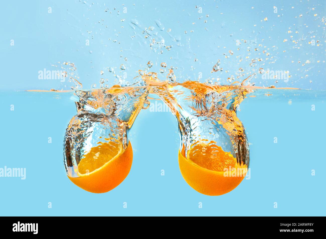 Falling of orange halves into water on light background Stock Photo - Alamy