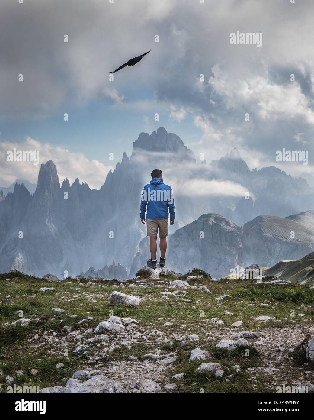 Beautiful shot of person standing on a rock looking at Three Peaks ...