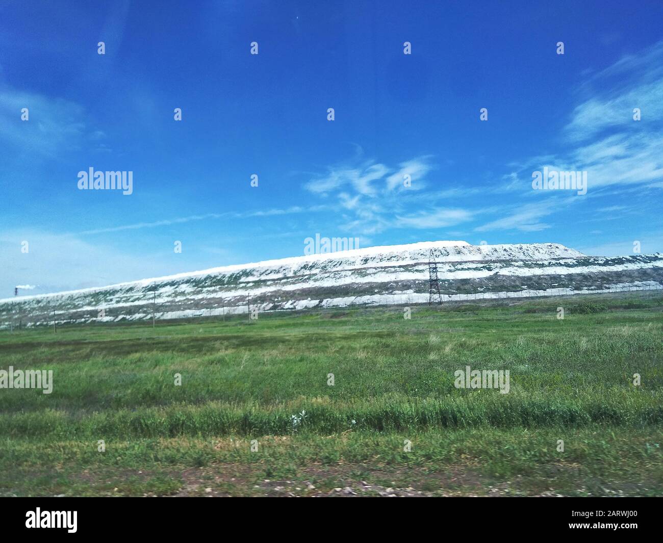 Low angle scenery of a green field surrounded by the white hills Stock ...