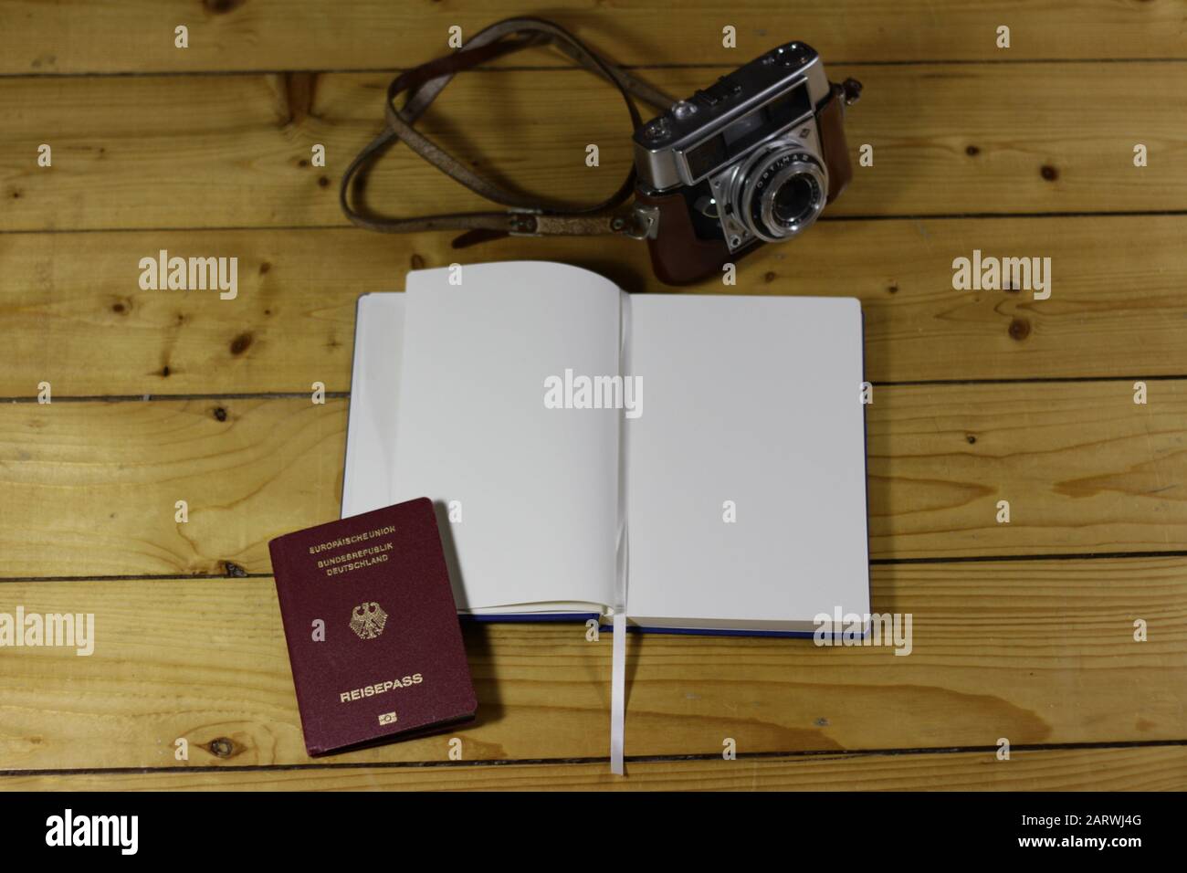 High angle shot of an open notebook next to a passport and a camera on ...