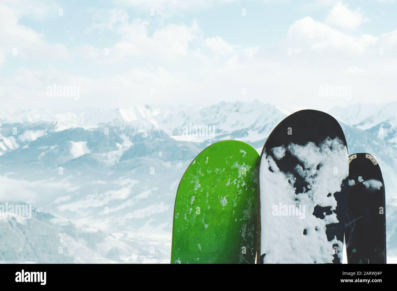 Closeup shot of snowboards covered in snow with mountains in white in ...