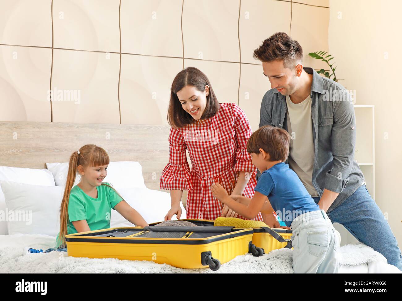 Happy family packing suitcase at home Stock Photo - Alamy