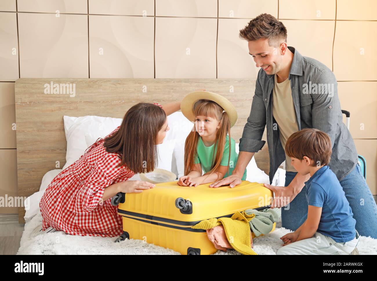 Happy family packing suitcase at home Stock Photo - Alamy