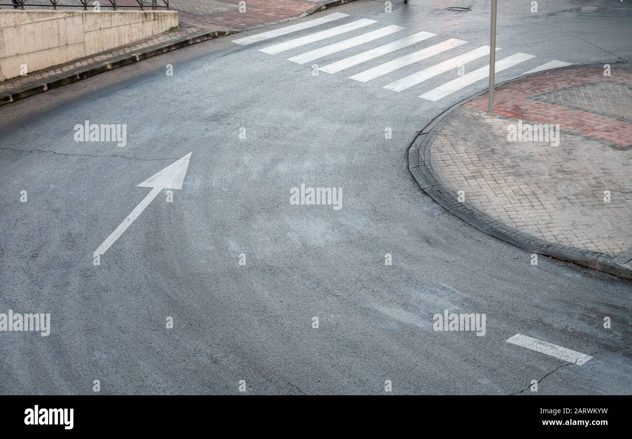 High angle shot of a road curve with a white directional arrow and ...