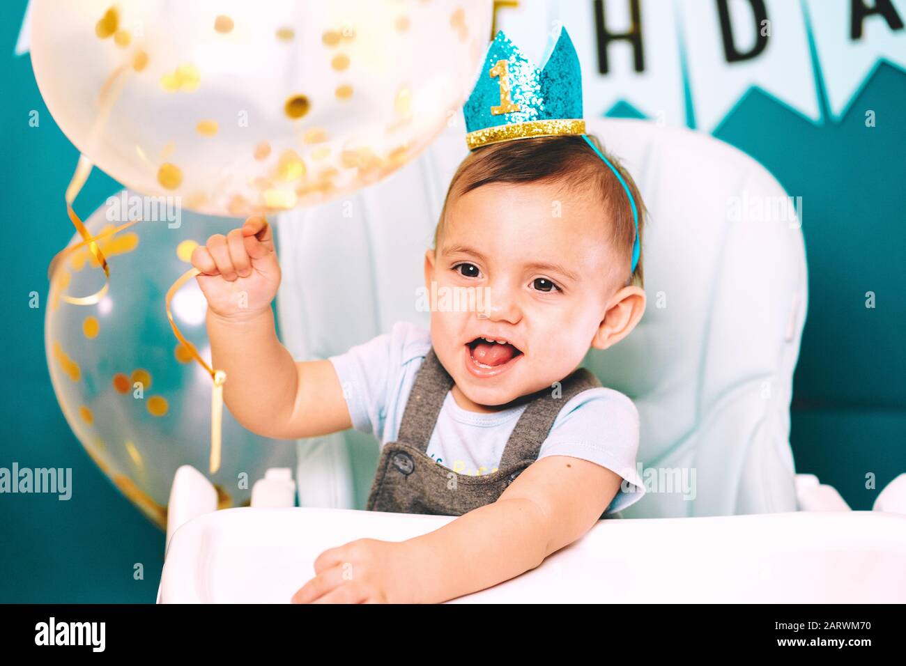 Cute baby boy sitting in his chair and playing with air balloon ...