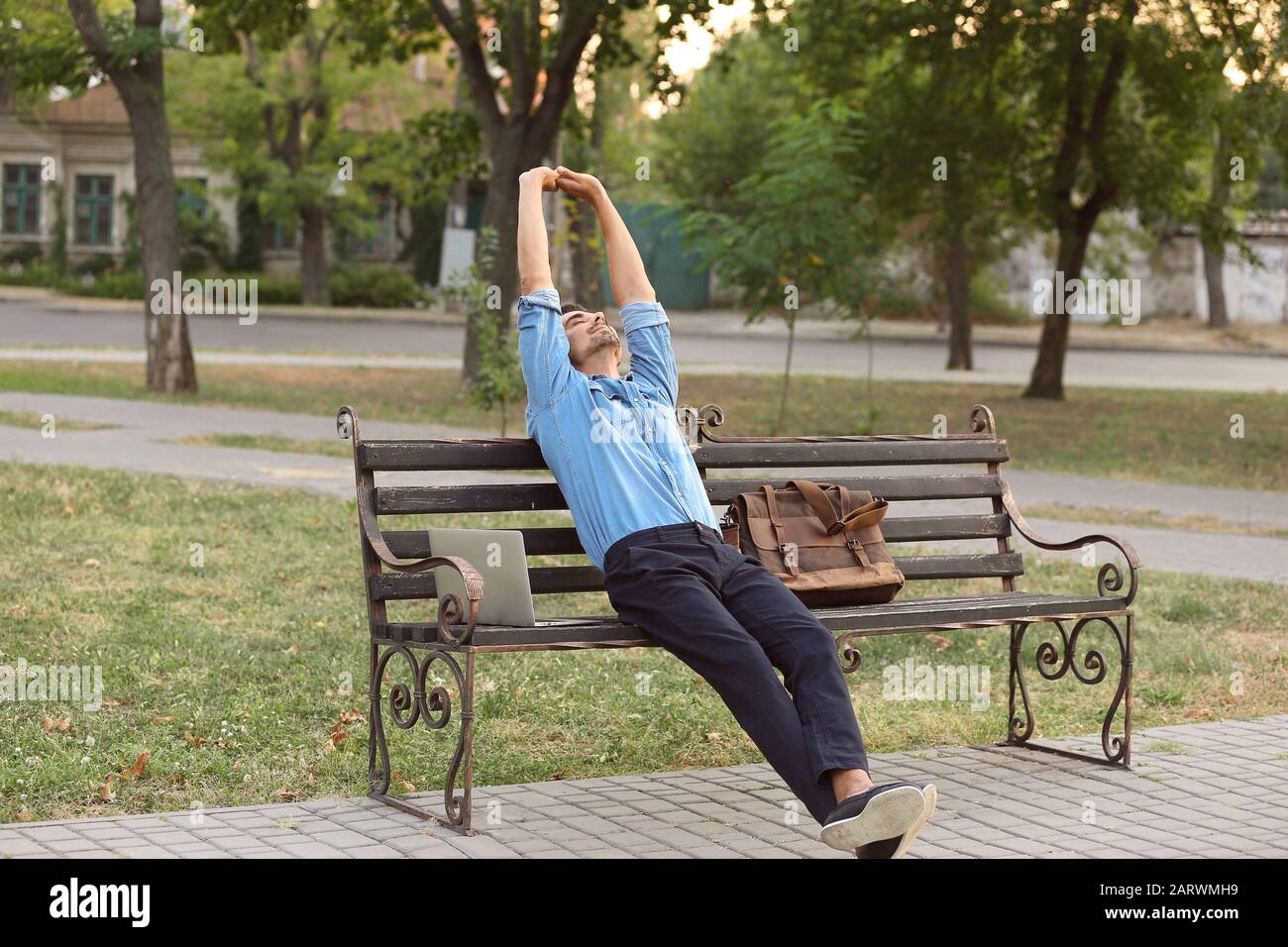 Portrait of handsome businessman relaxing on bench outdoors Stock Photo ...