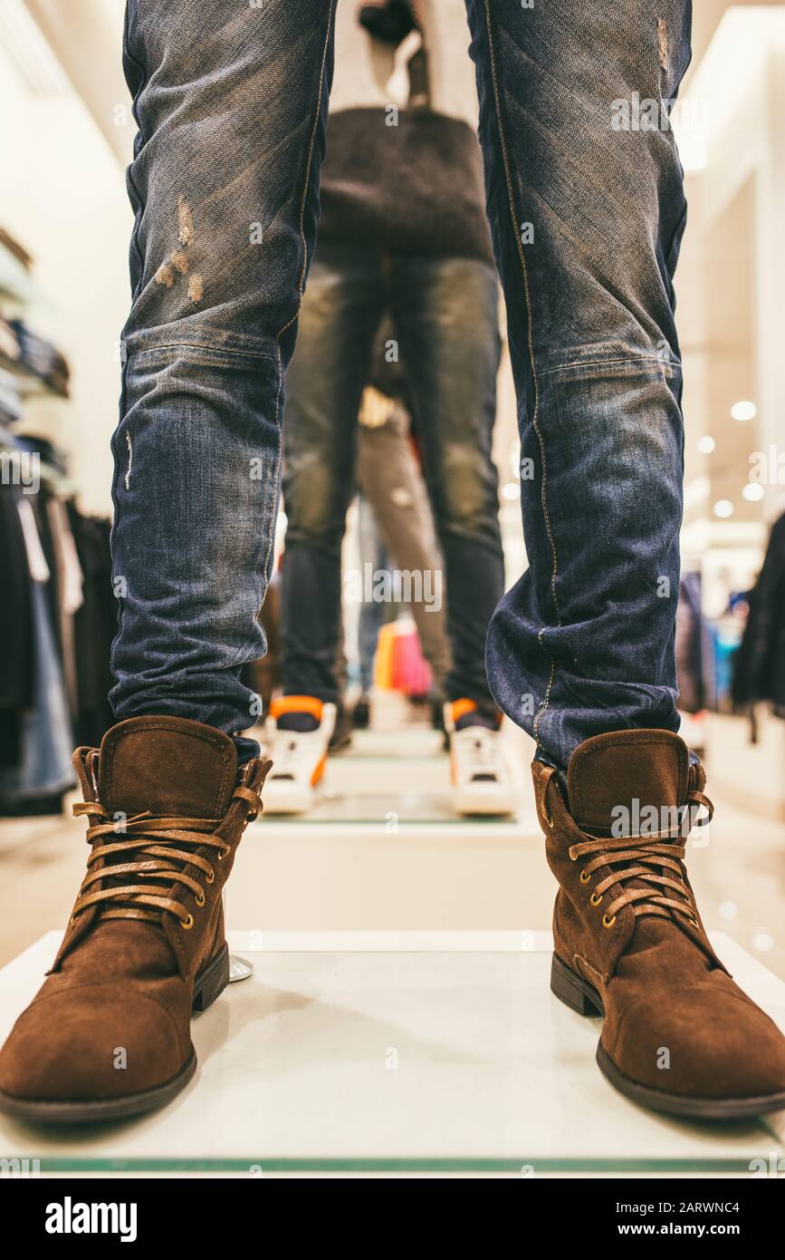 legs of mannequins in the store dressed in blue jeans and brown leather ...