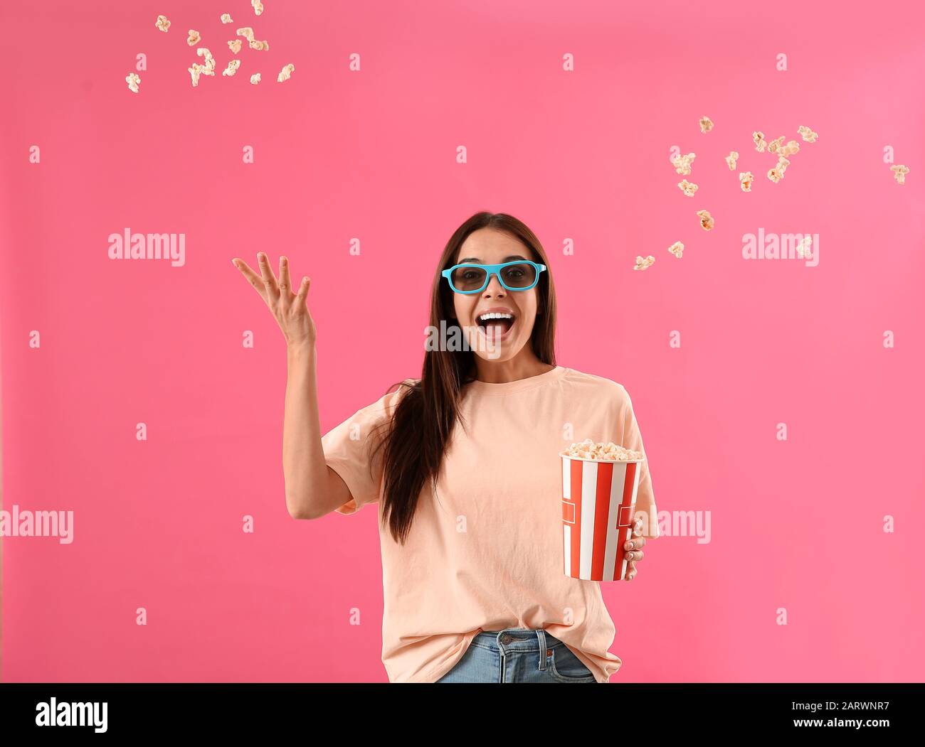 Happy woman throwing popcorn on color background Stock Photo - Alamy