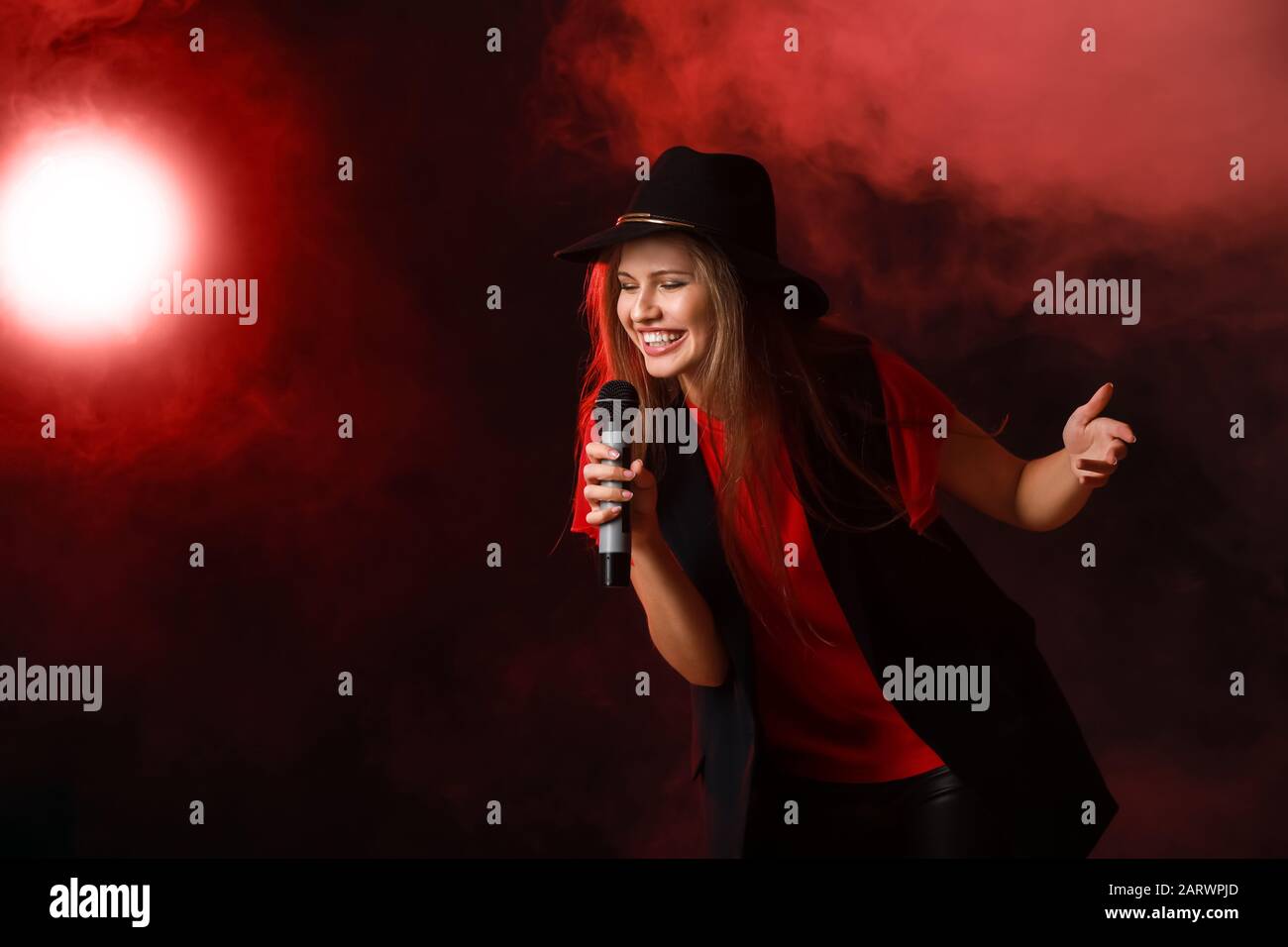 Beautiful young female singer with microphone on stage Stock Photo - Alamy