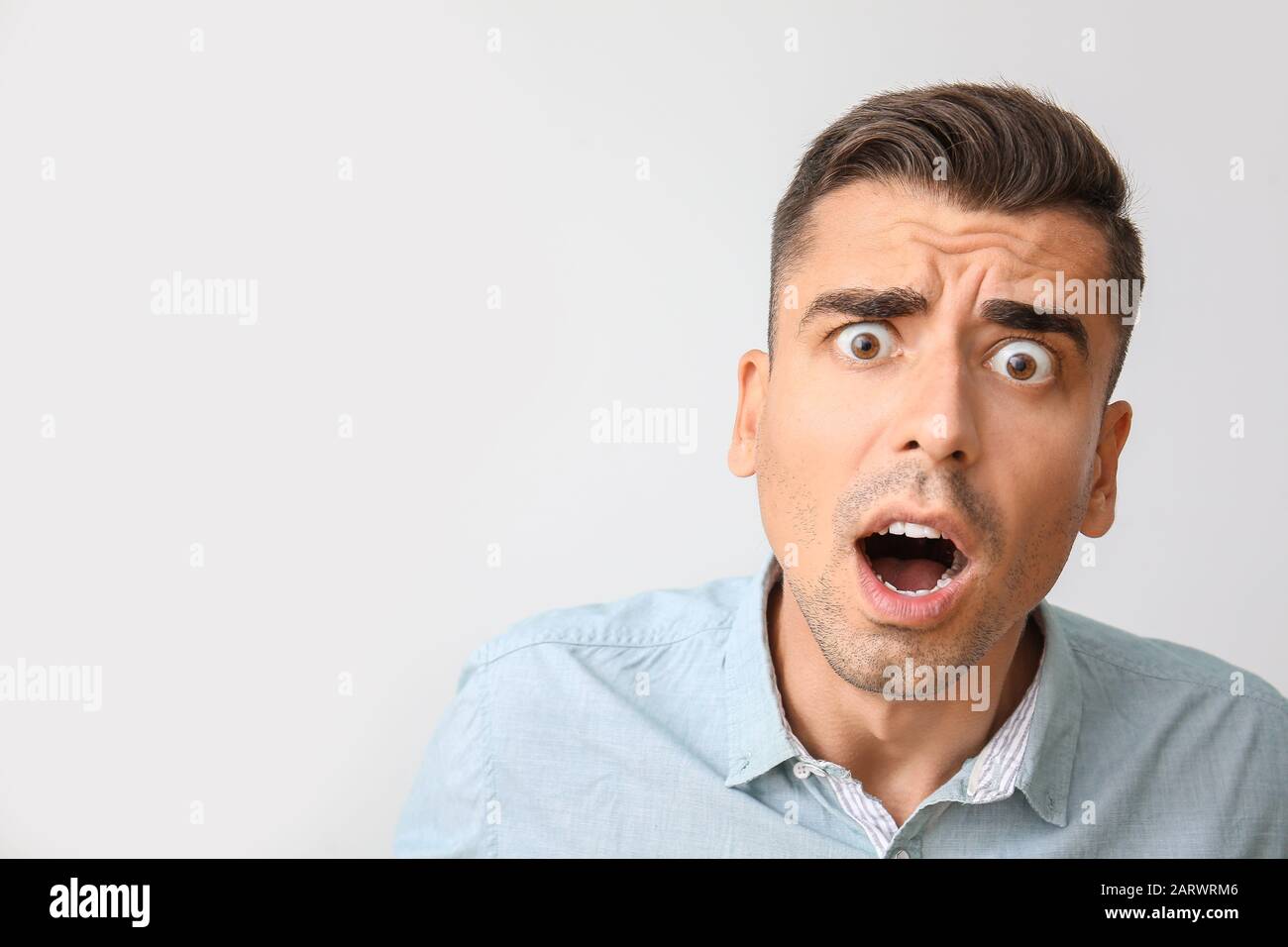 Shocked young man on light background Stock Photo - Alamy