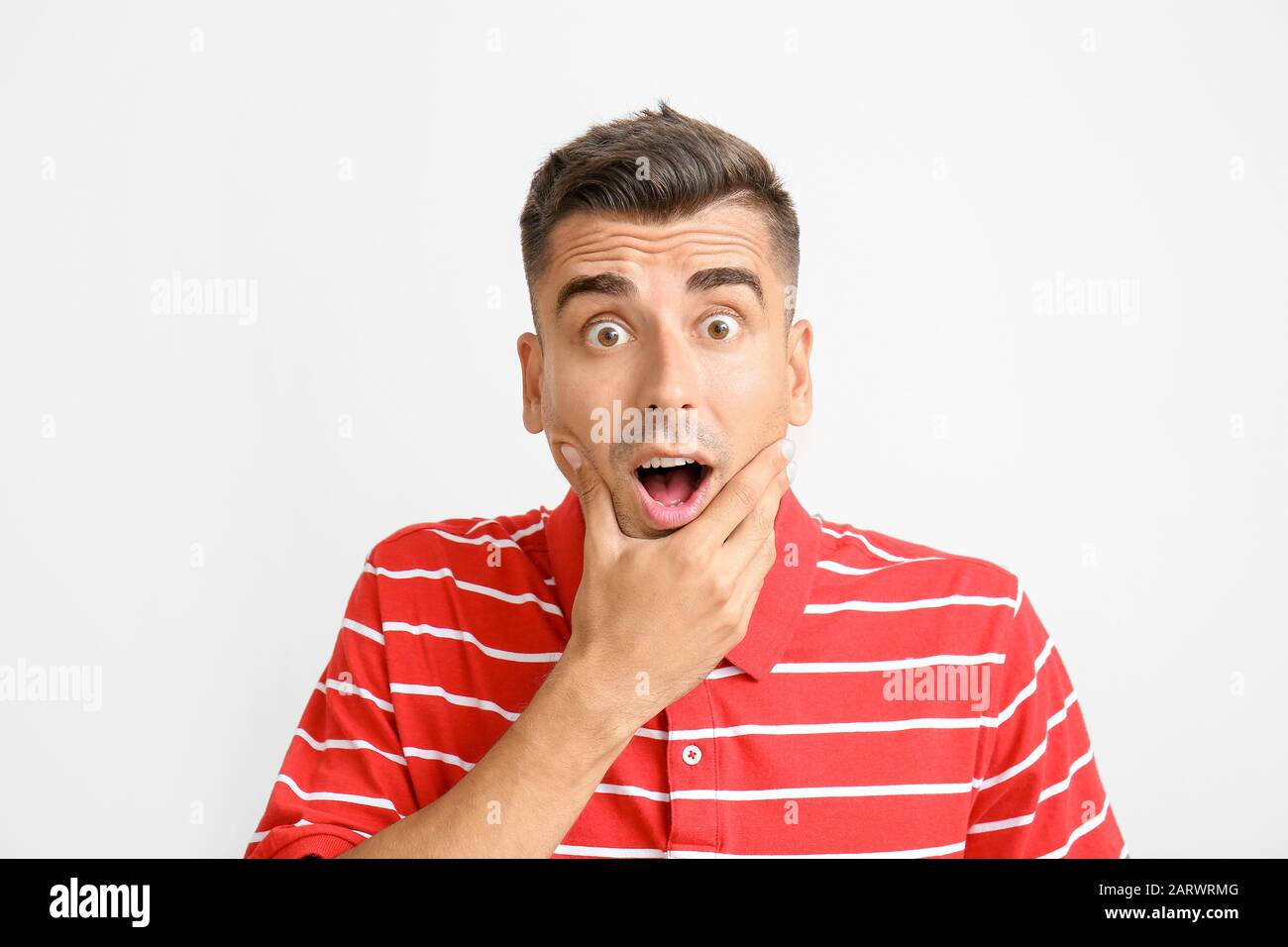 Shocked young man on light background Stock Photo - Alamy