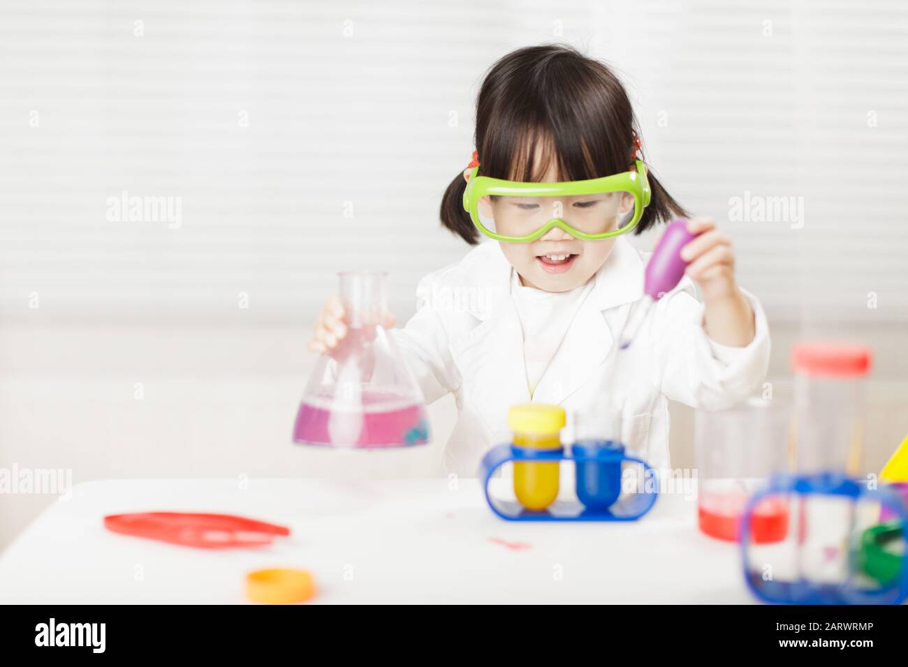toddler girl pretend play scientist role at home against white ...