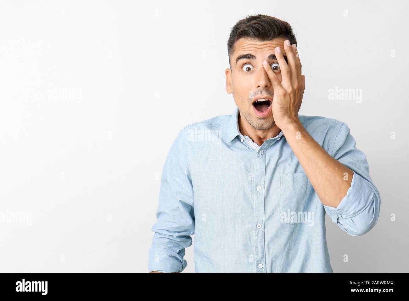 Shocked young man on light background Stock Photo - Alamy