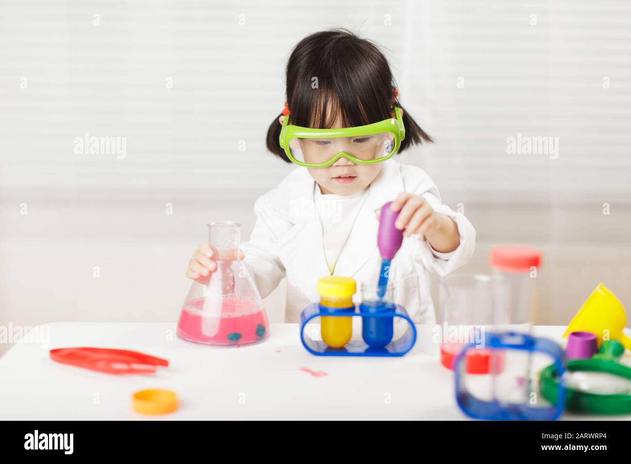 toddler girl pretend play scientist role at home against white ...