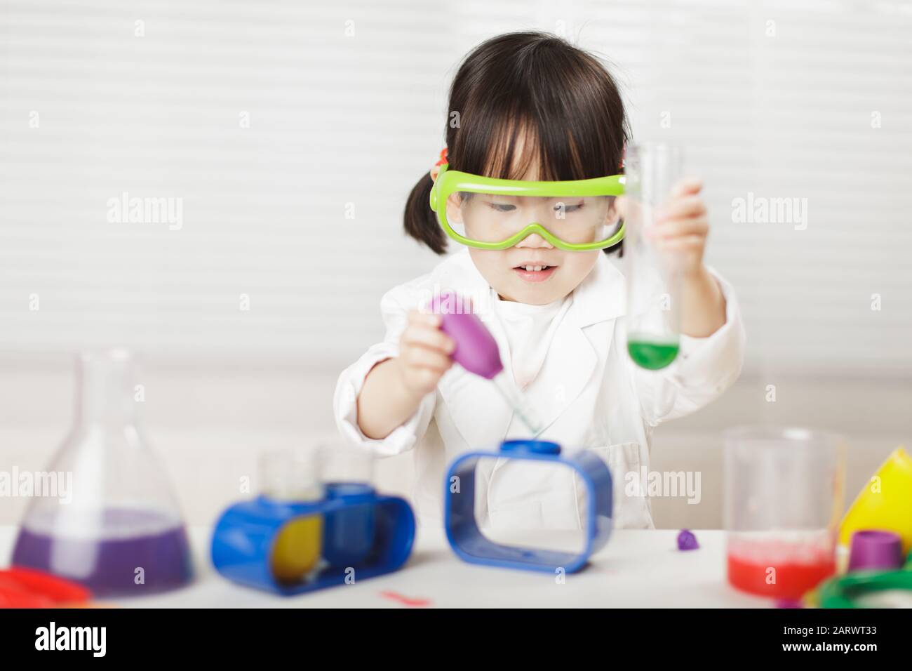 toddler girl pretend play scientist role at home against white ...