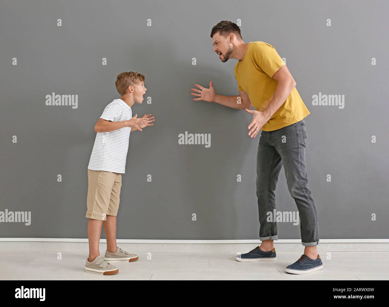 Arguing father and his little son near grey wall Stock Photo - Alamy