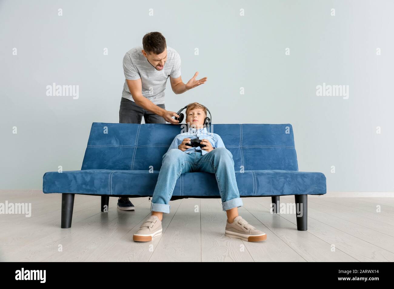 Little boy playing videogame and ignoring his angry father at home ...