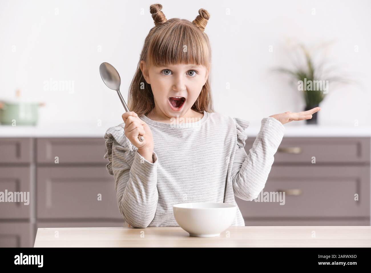 Surprised little girl eating in kitchen Stock Photo - Alamy