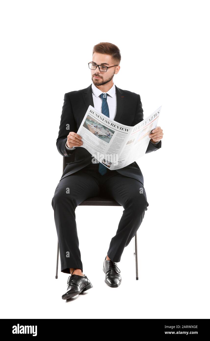Handsome businessman with newspaper sitting on chair against white ...