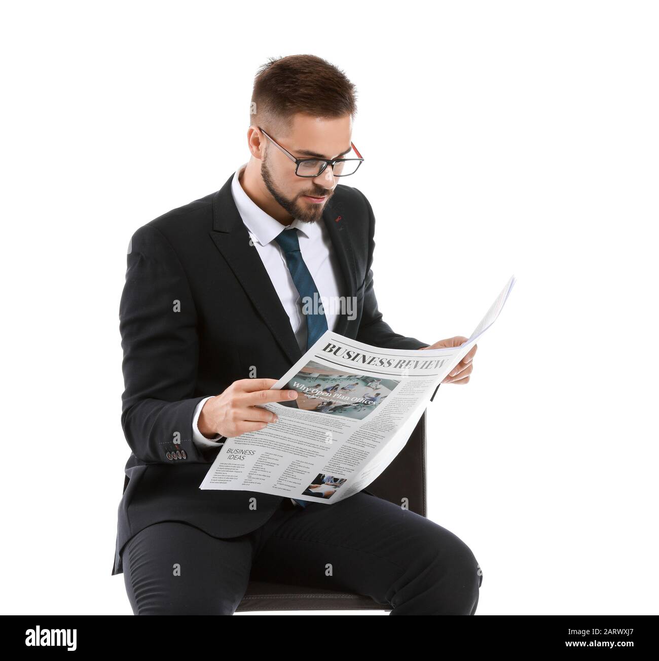 Handsome businessman with newspaper sitting on chair against white ...