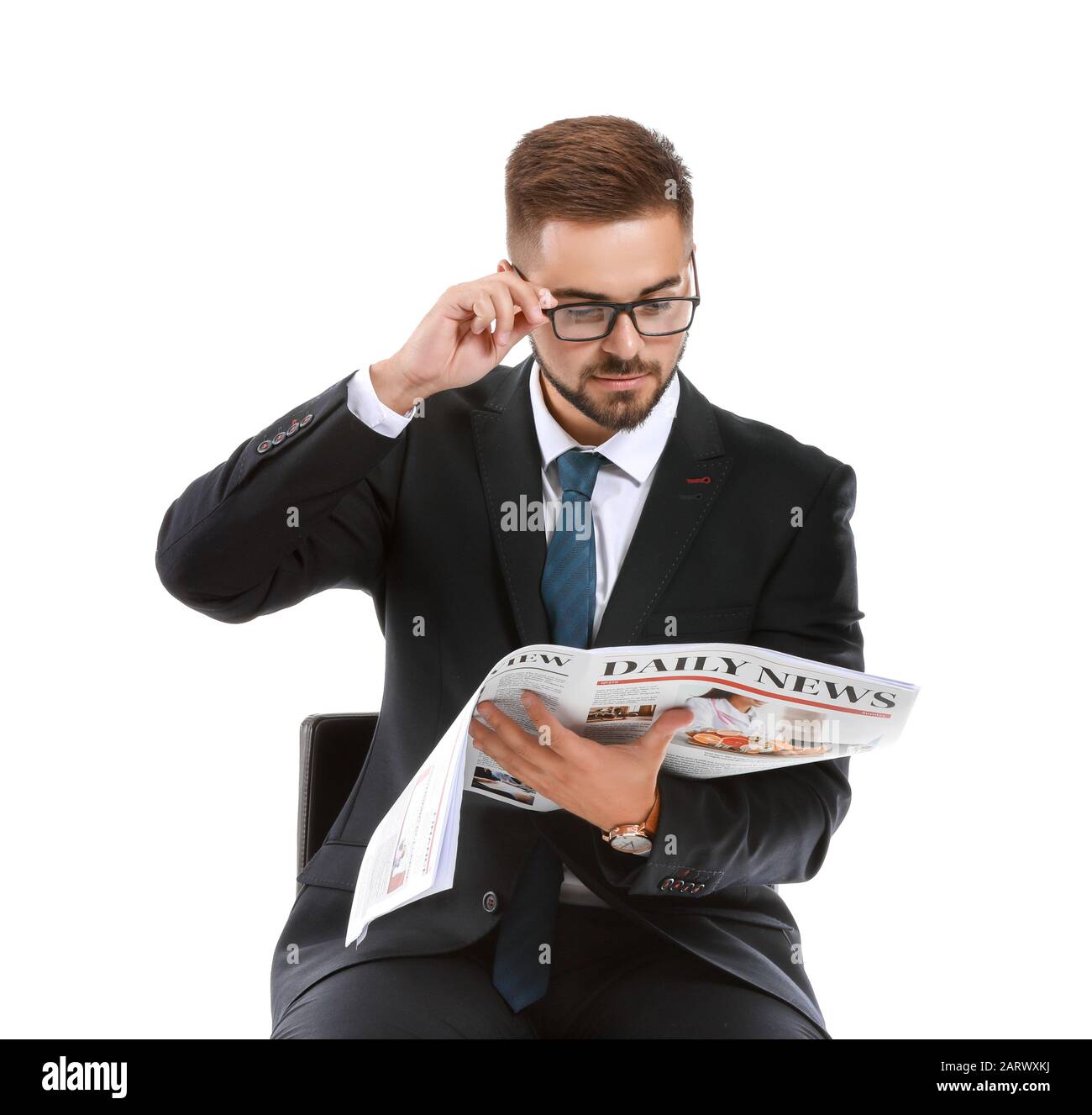 Handsome businessman with newspaper sitting on chair against white ...