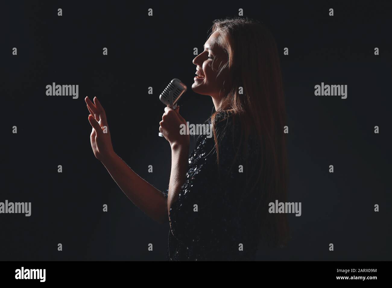 Beautiful young female singer with microphone on stage Stock Photo - Alamy