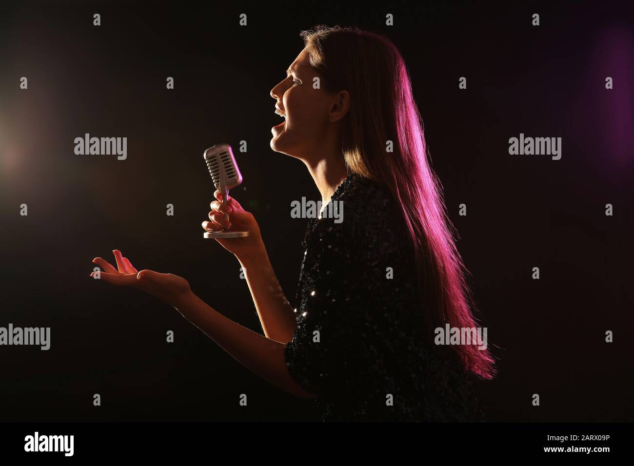 Beautiful young female singer with microphone on stage Stock Photo - Alamy