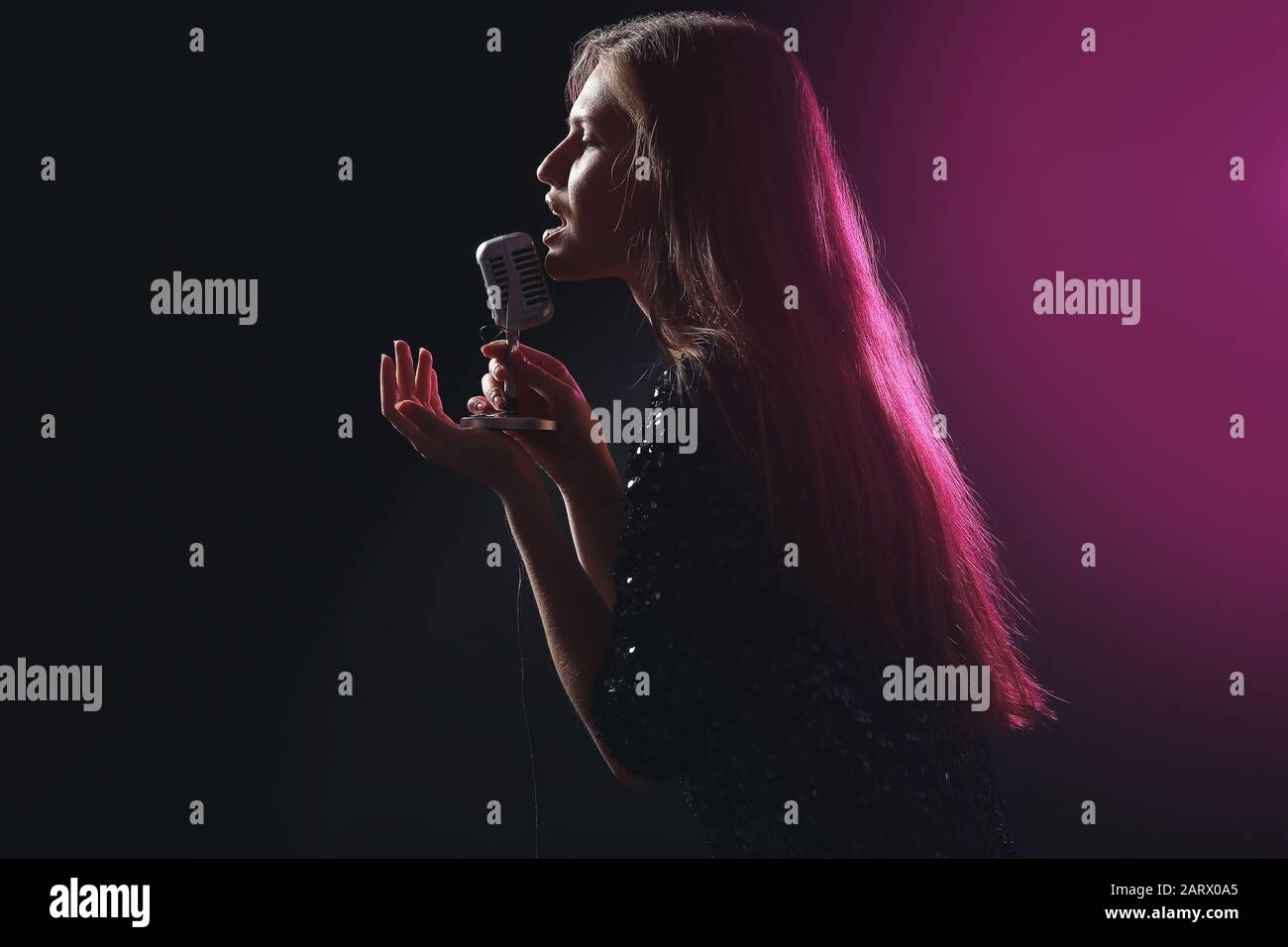 Beautiful young female singer with microphone on stage Stock Photo - Alamy