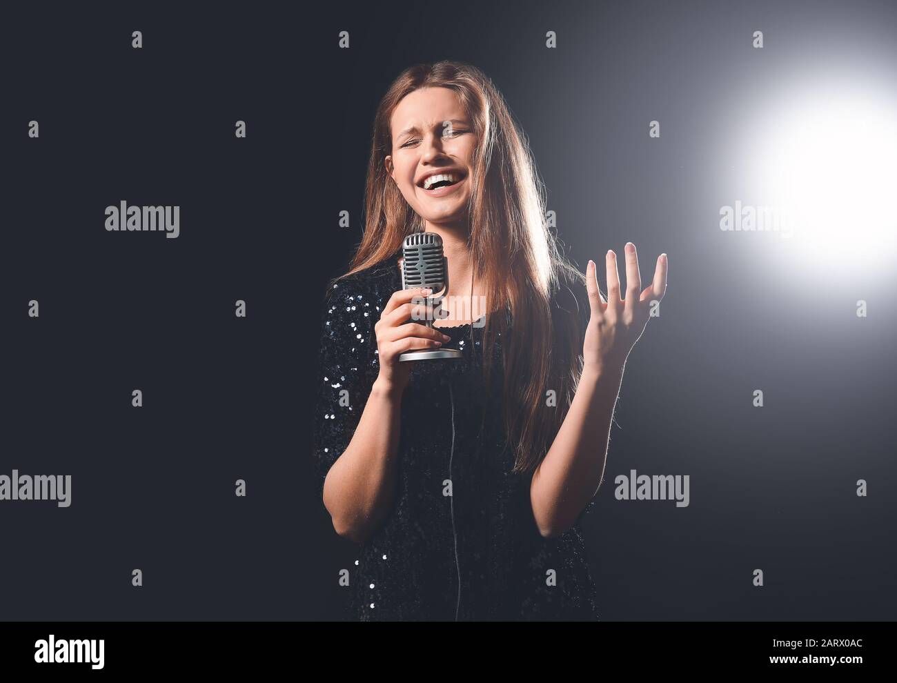 Beautiful young female singer with microphone on stage Stock Photo - Alamy