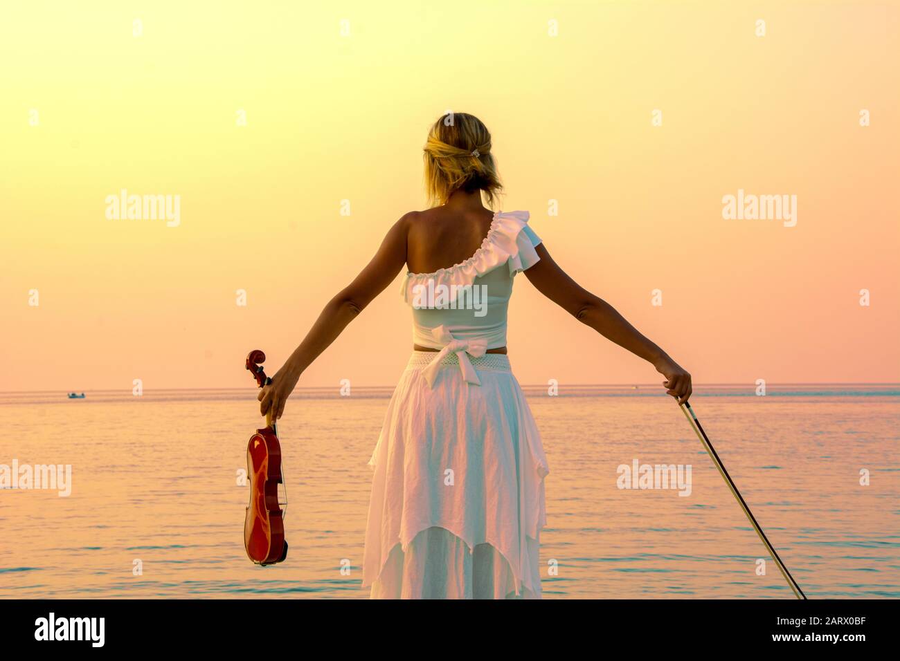 Beautiful woman playing violin at the sea with sunset background Stock ...