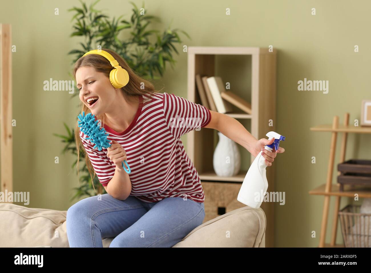 Beautiful young woman singing while cleaning her flat Stock Photo - Alamy